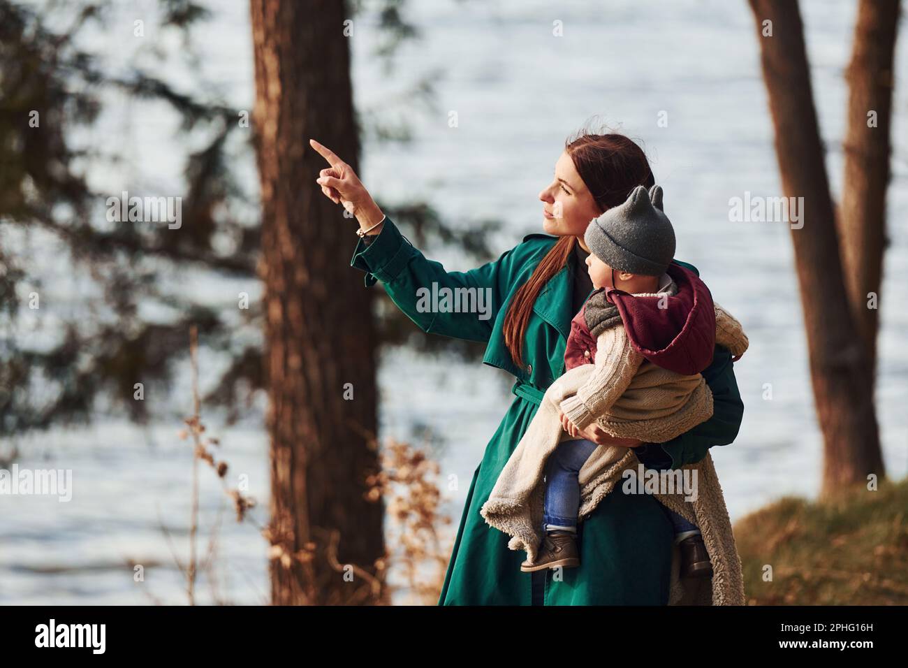 Mother with her little son have a walk in spring forest at daytime ...