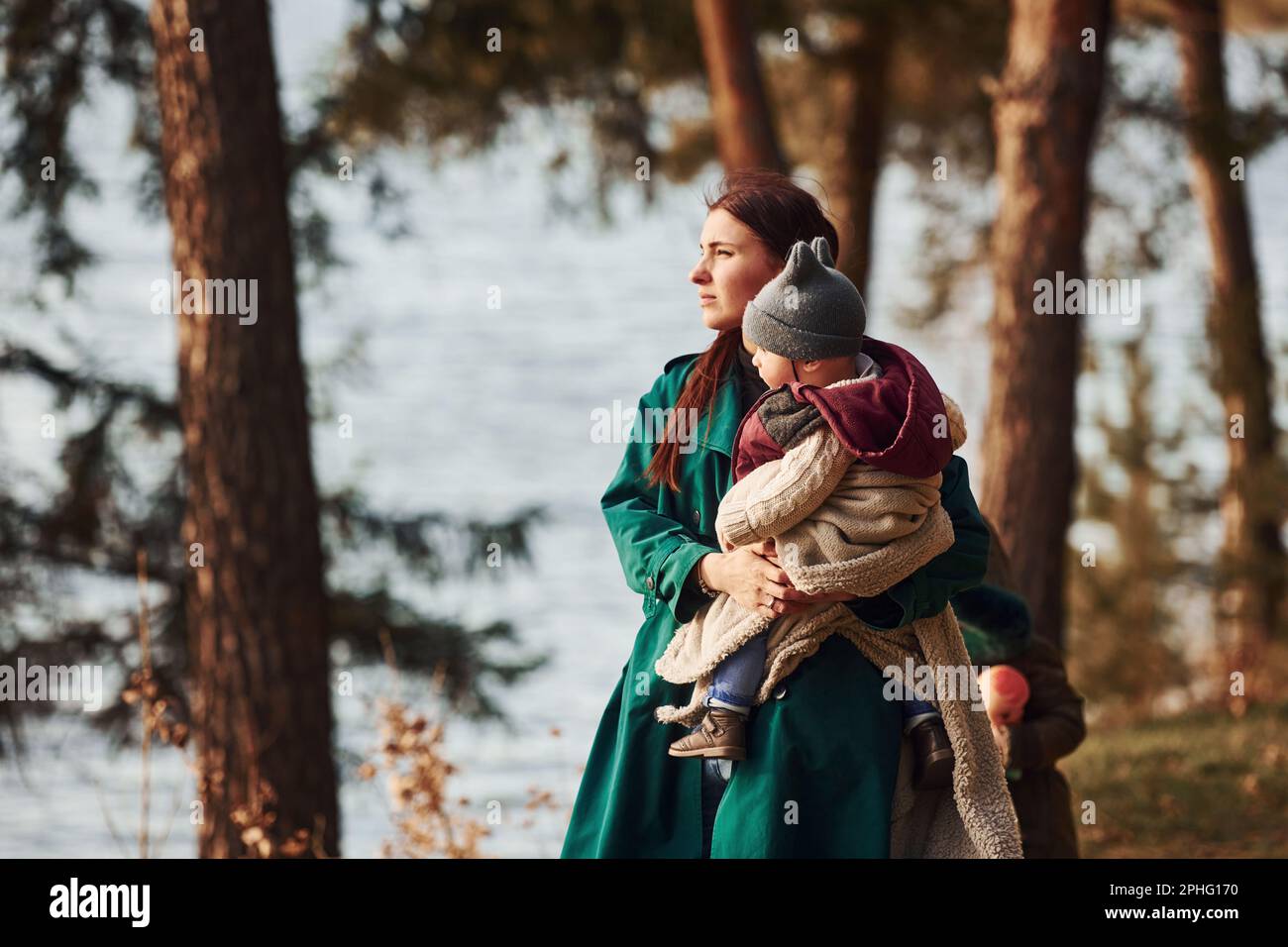 Mother with her little son have a walk in spring forest at daytime ...