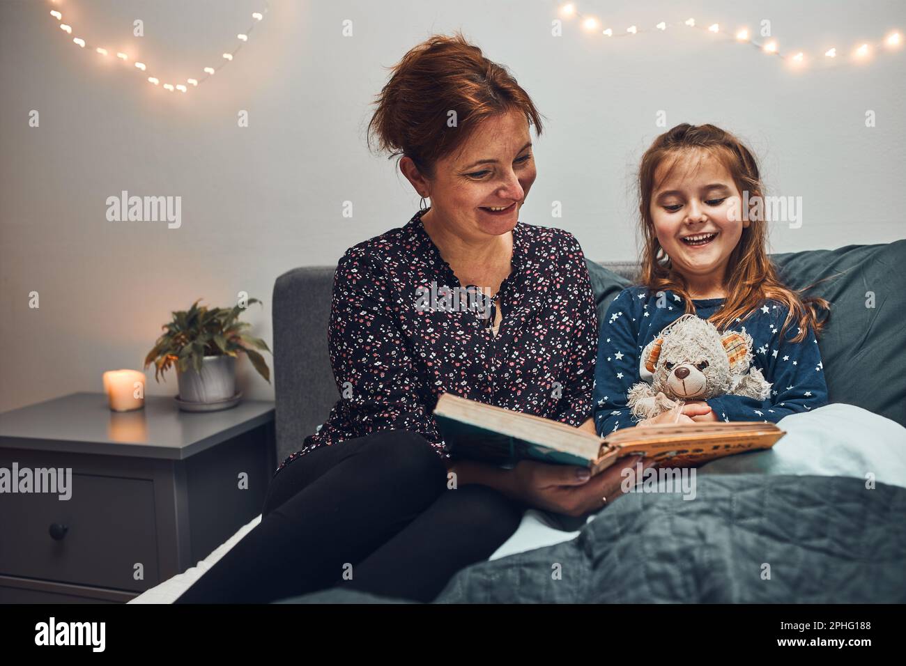 Mother reading book her daughter in bed before going to sleep. Reading ...