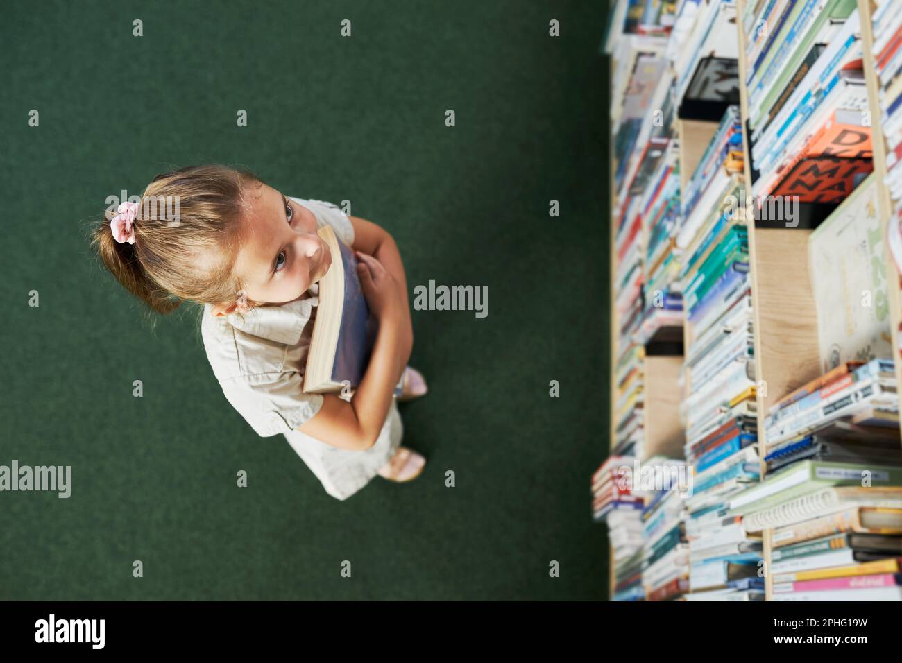 Sttudent looking at top bookshelf in school library. Smart girl ...