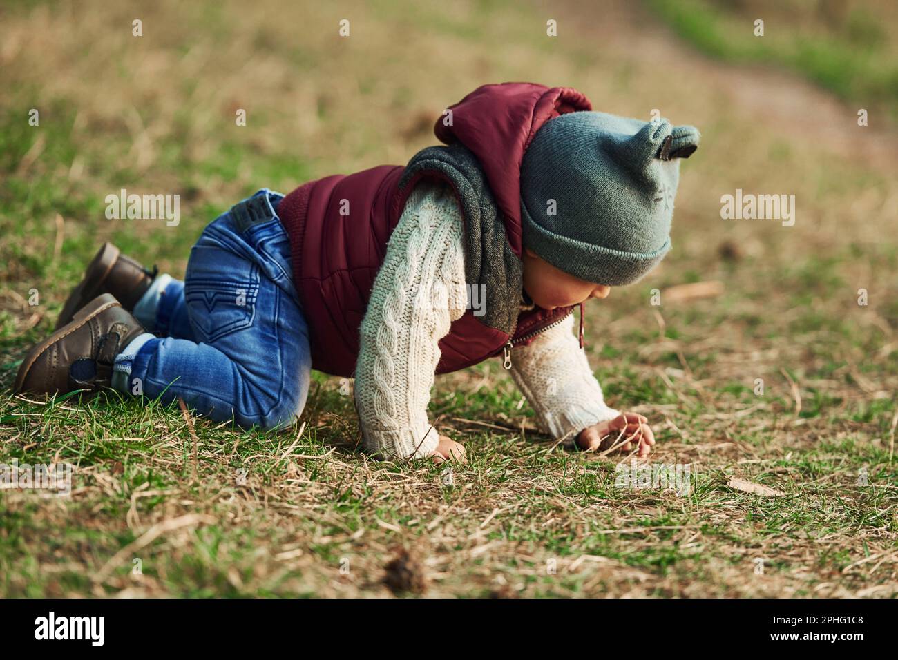 Little boy in warm clothes lying down on ground of field on grass Stock ...