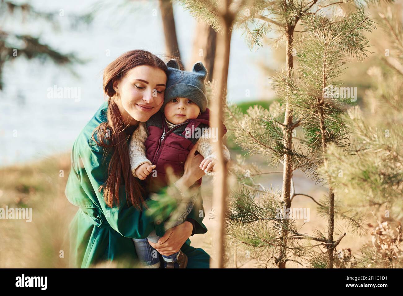 Mother with her little son have a walk in spring forest at daytime ...