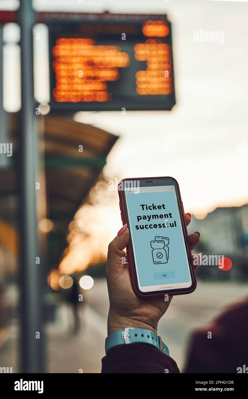 Woman buying ticket online near bus stop before ride. Person paying for ...