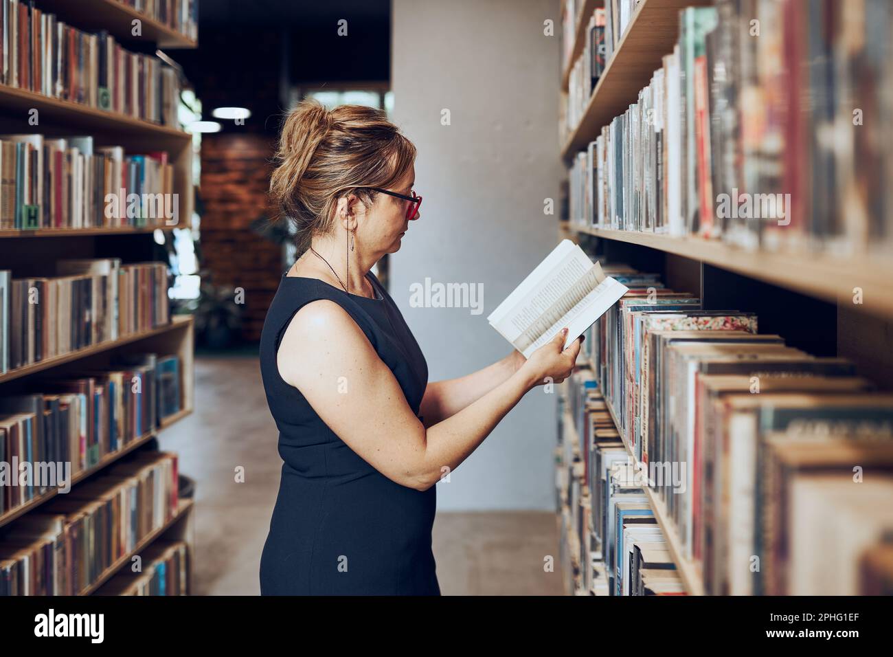 Woman reading book in public library. Teacher searching for literature ...