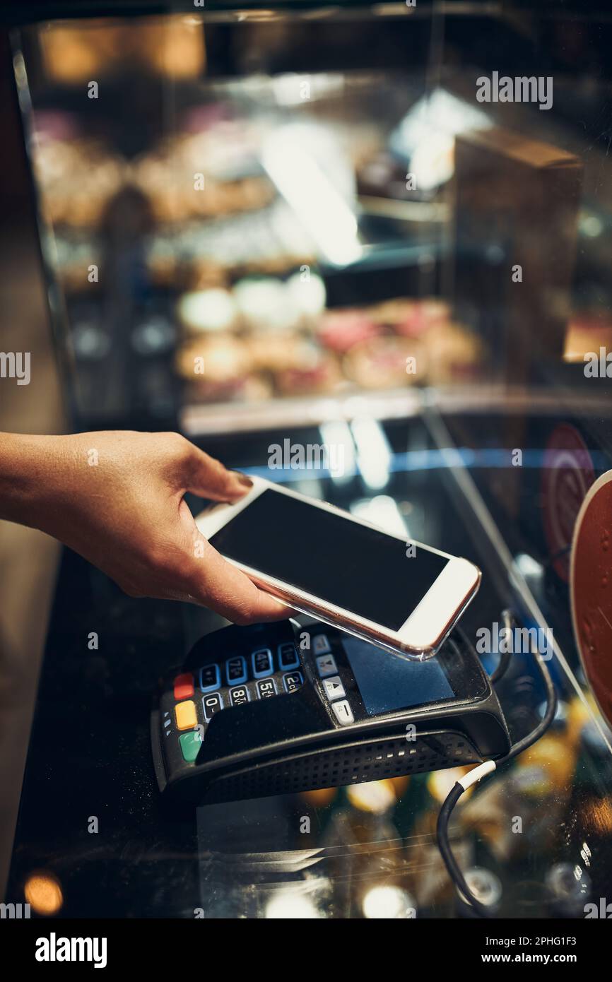 Woman paying in coffee shop using contactless method of payment via ...