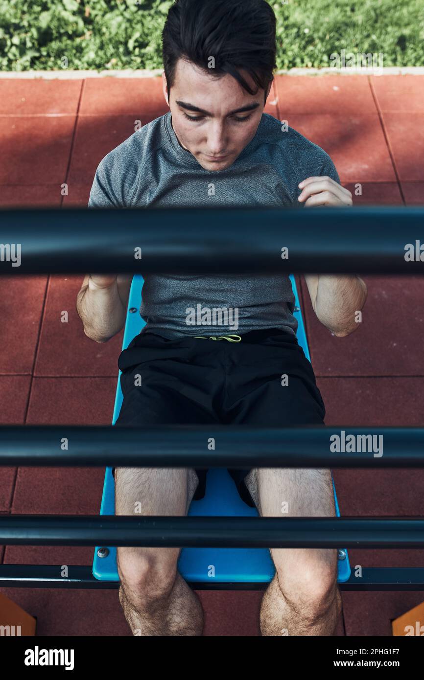 Young man doing sit-ups during his workout in a modern calisthenics ...
