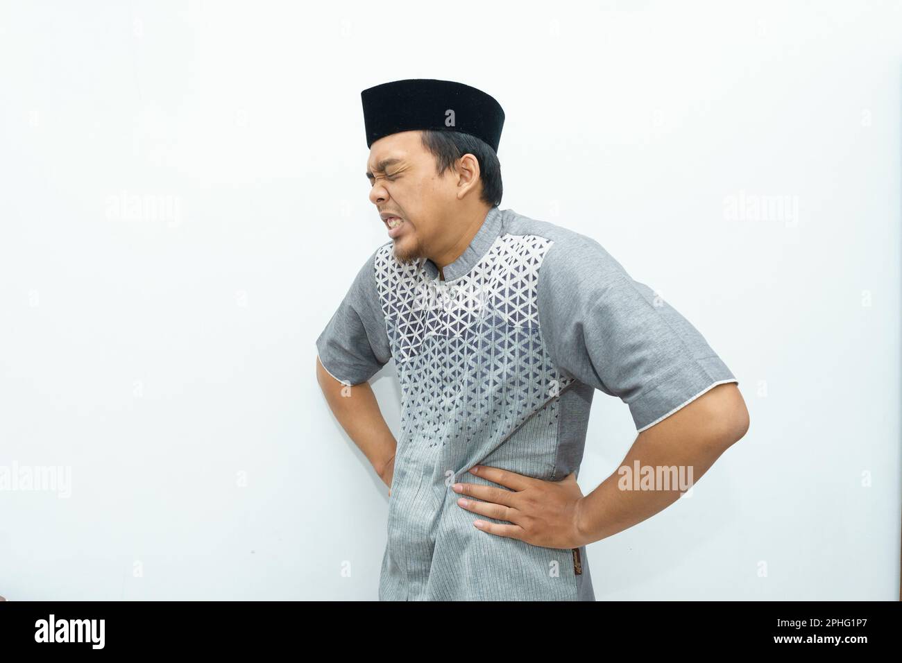 Portrait of an Asian Indonesian Muslim man placing his hands on stomach ...