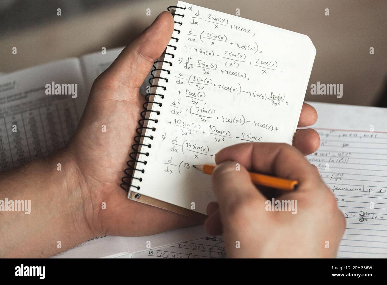 Math formulas are written in pencil in a notebook holding man in Stock ...