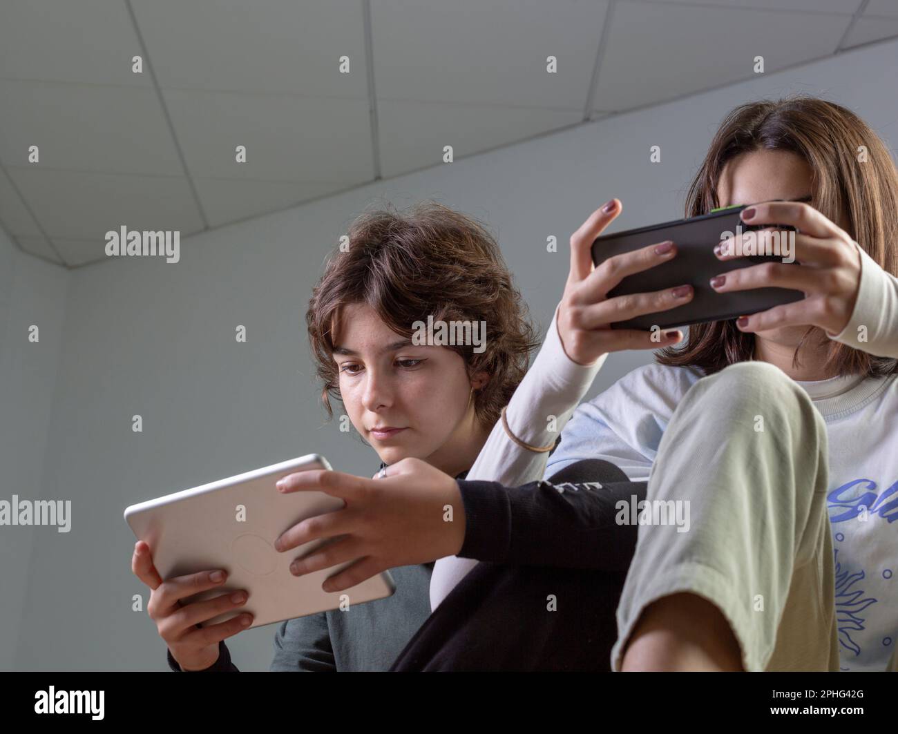 Two teenagers use electronic devices to access the internet. Tablet ...