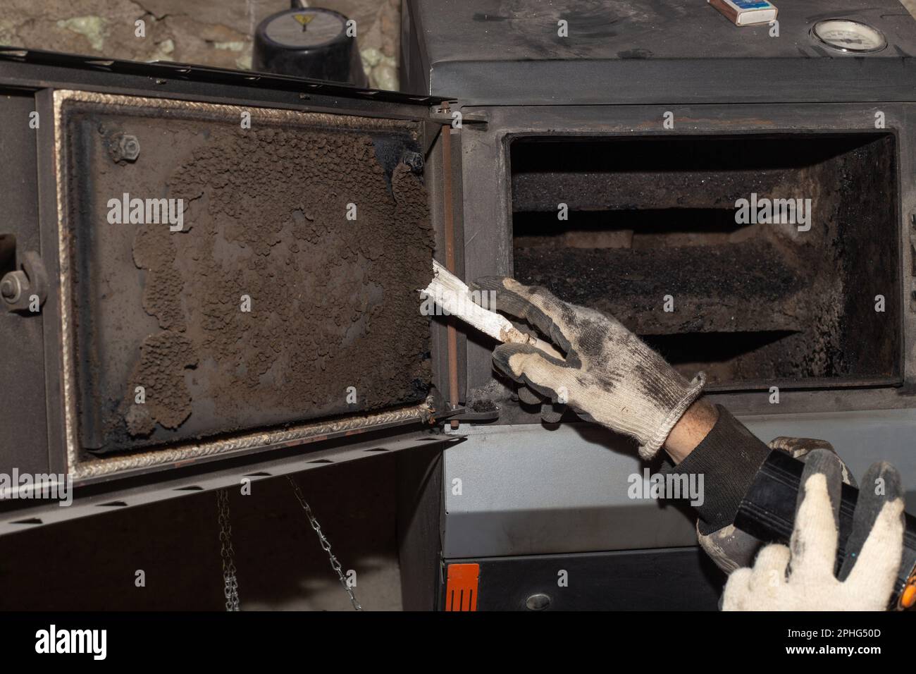 A man cleans a solid fuel boiler from soot and soot. Maintenance of ...
