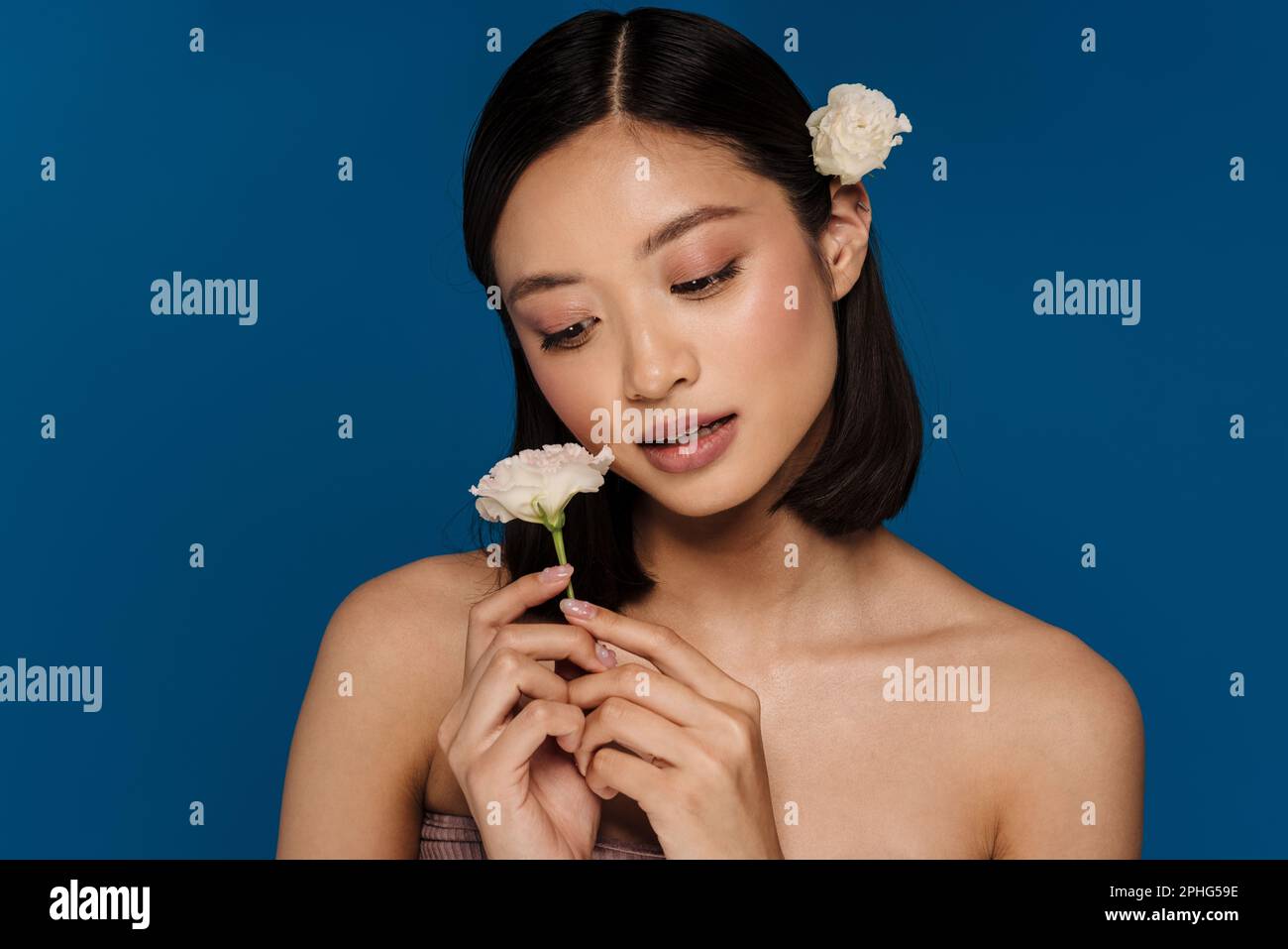 Young beautiful asian woman with opened mouth with flower on ear ...