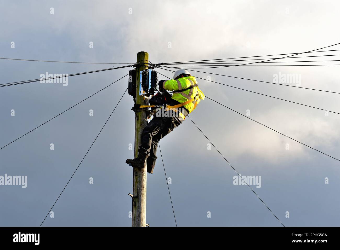 A British Telecoms engineer installing fibre optic cable at the top of ...