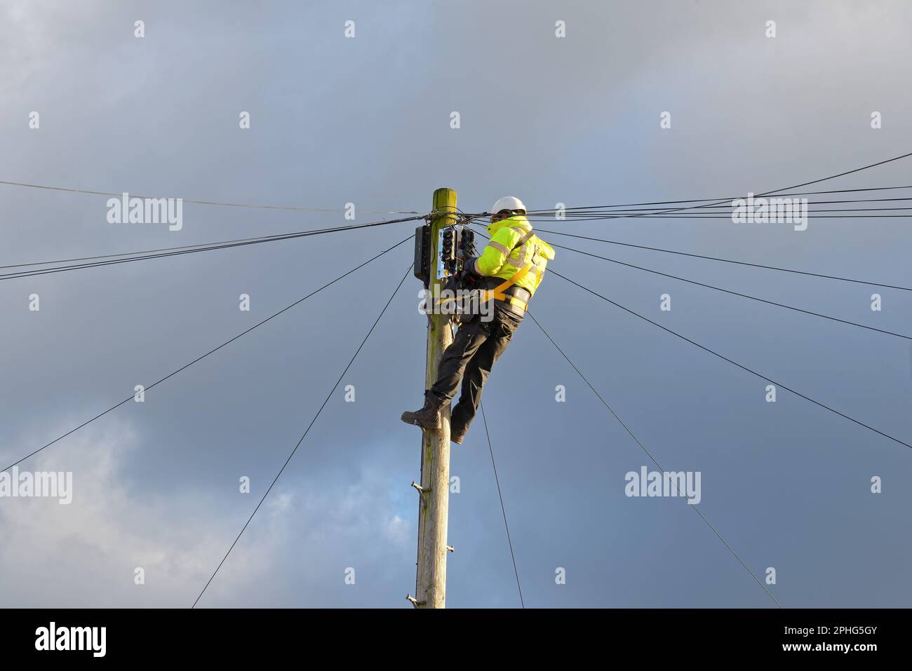A British Telecoms engineer installing fibre optic cable at the top of ...