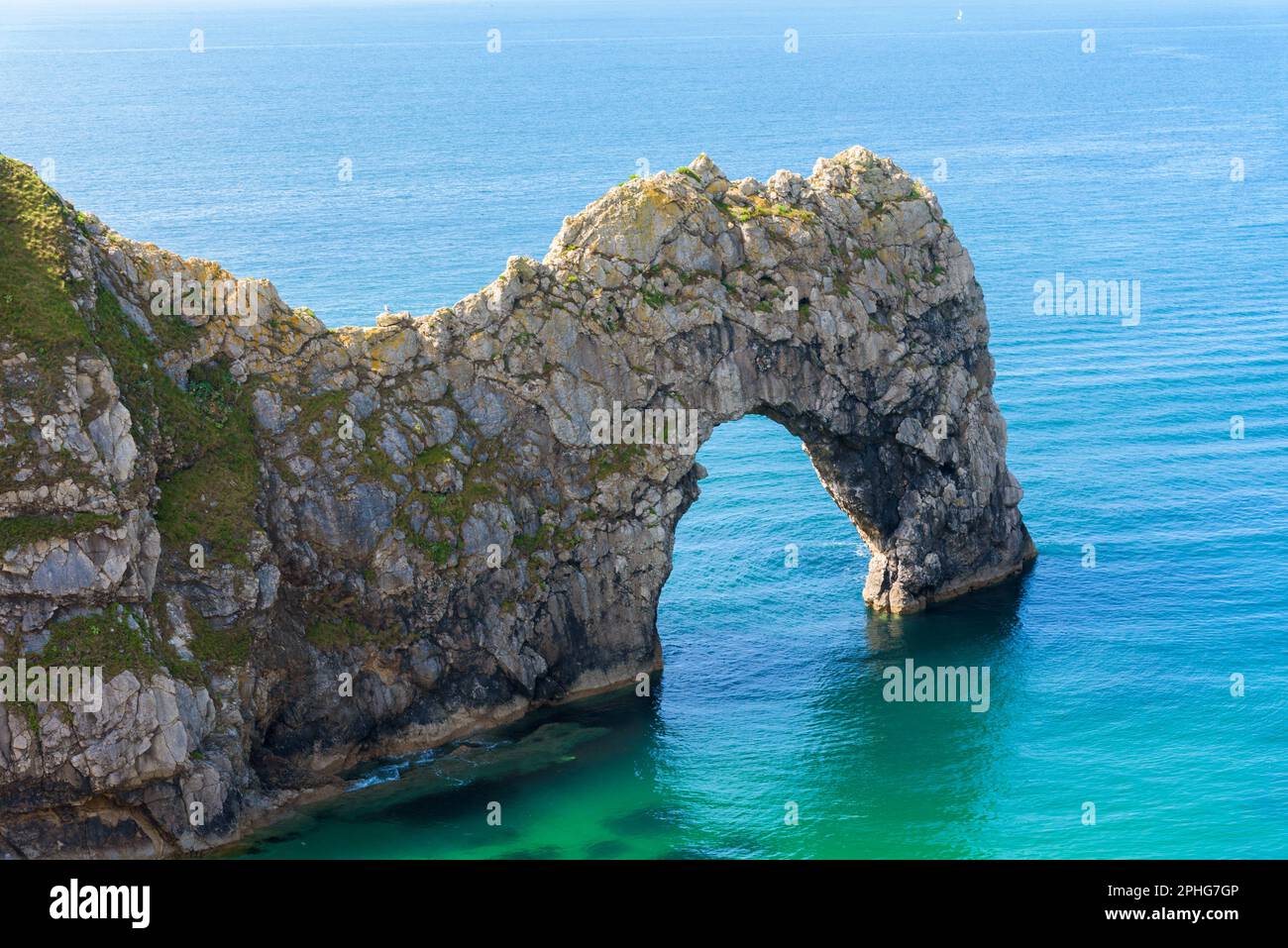 Durdle Door natural arch with its bay and beach. Clear sea water near ...