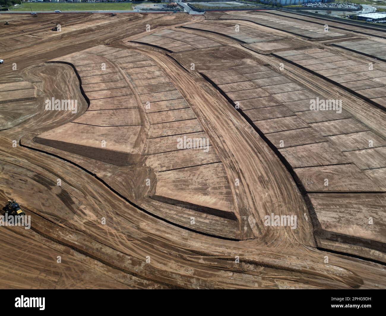 Industrial landscape featuring two orange tractors on a dirt road at a ...