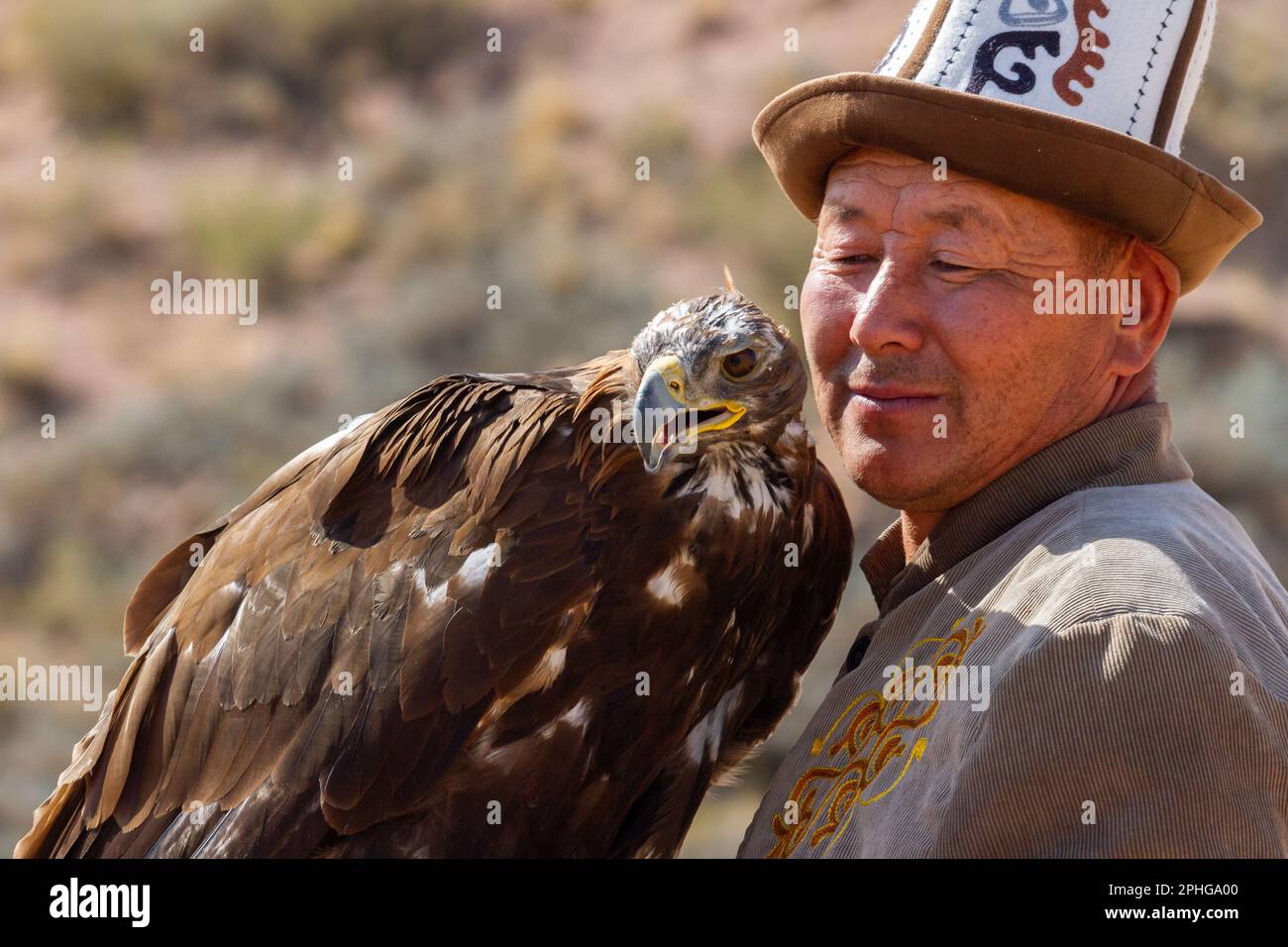 Kyrgyz hunter or Berkutchi hugging a golden eagle, Kyrgyzstan Stock ...