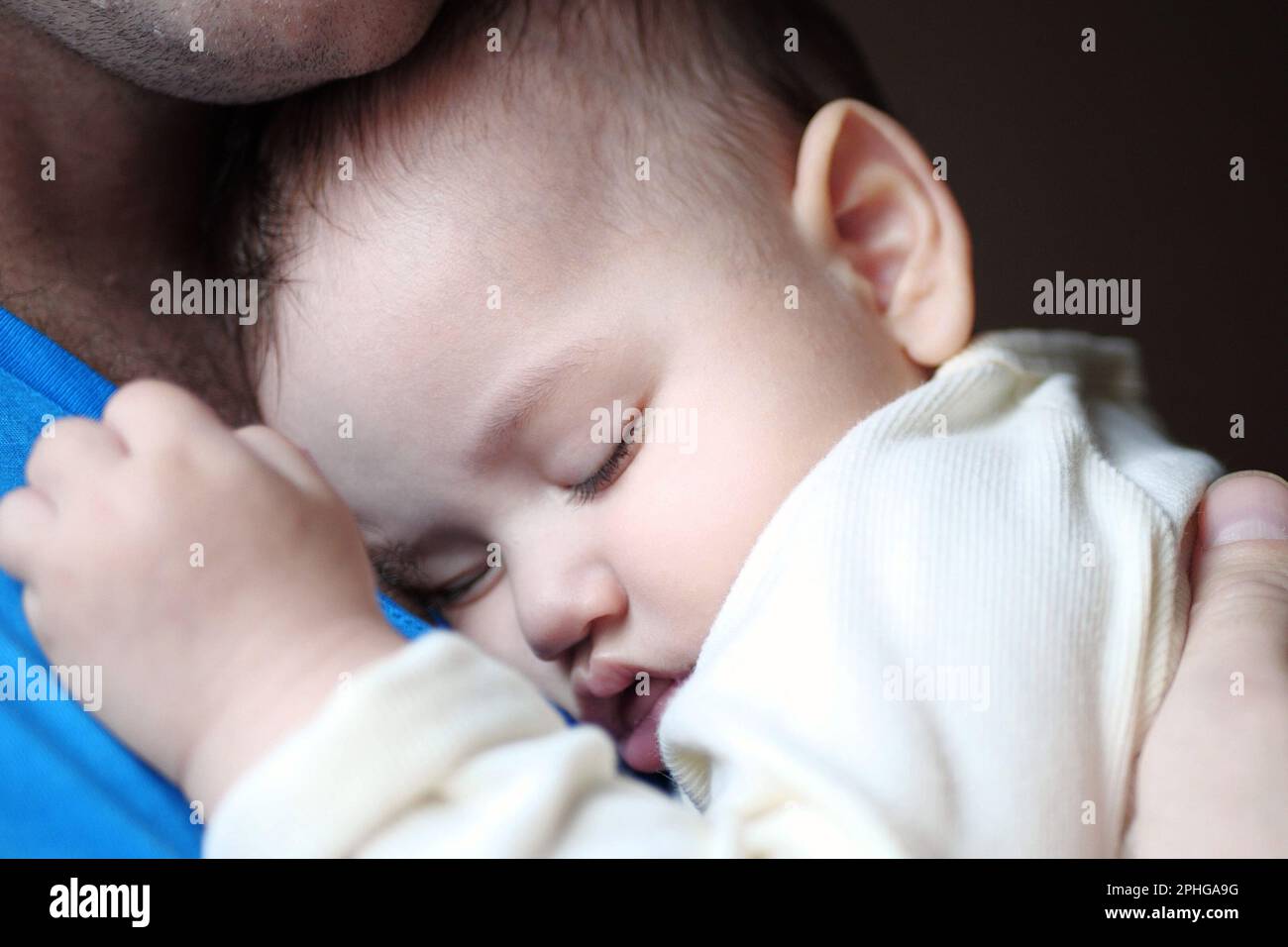 Cute newborn baby sleeping in father arms close up. A loving father ...