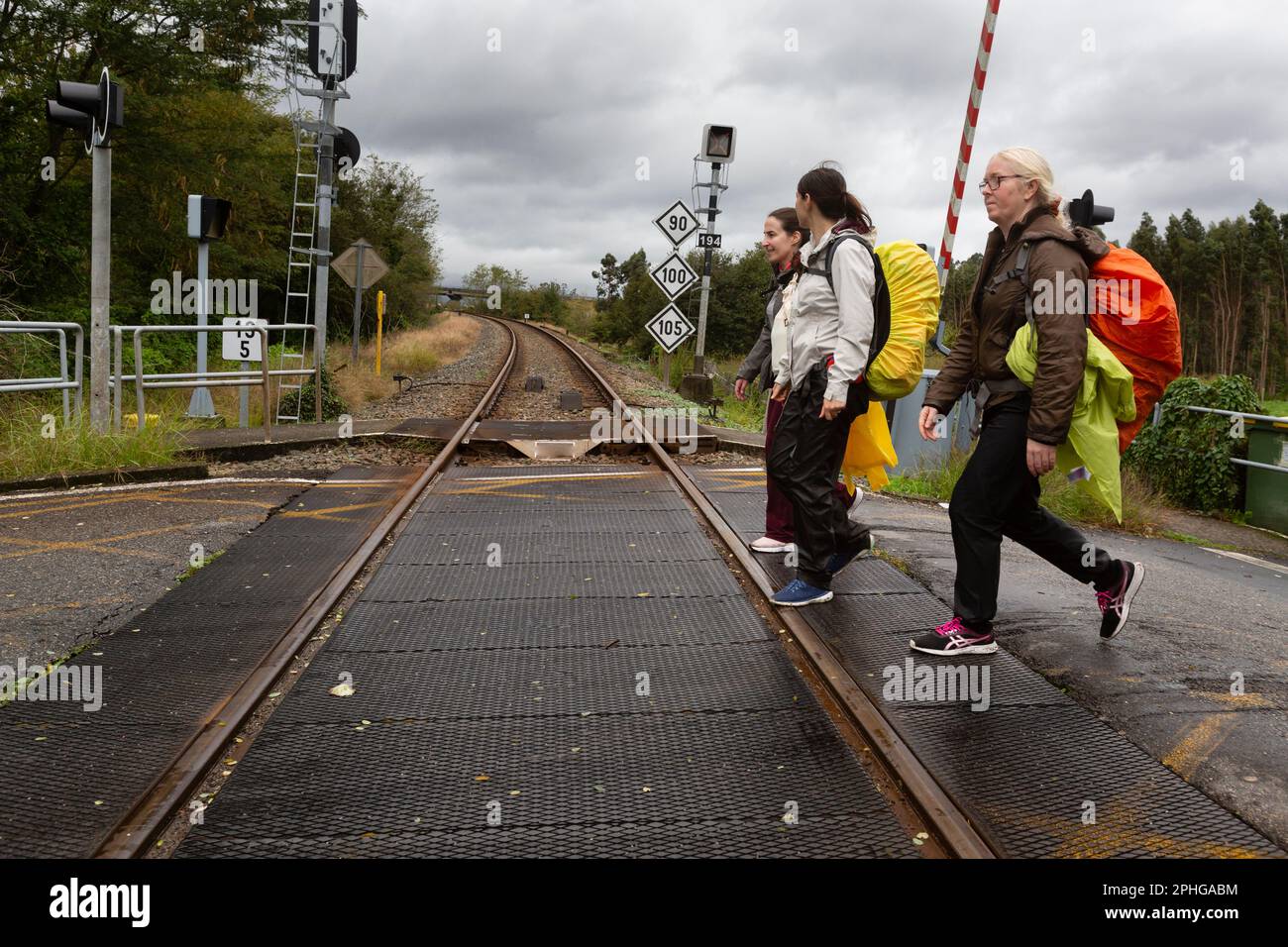 Three pilgrims walk the Portuguese Camino de Santiago on a rainy day ...