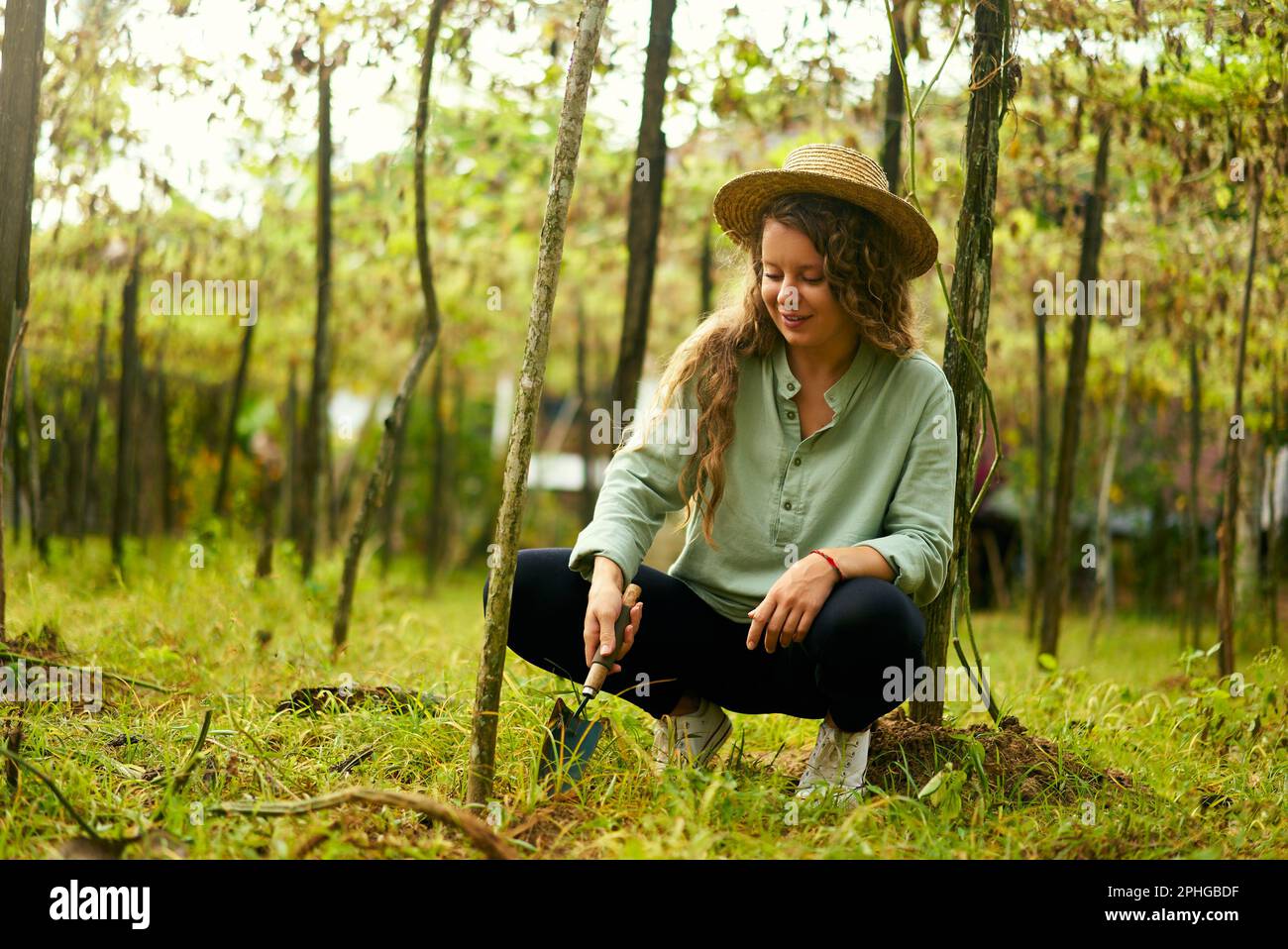 Young caucasian female farmer loosening the soil with garden shovel ...