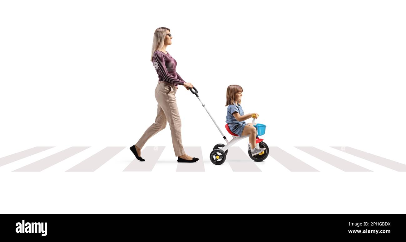 Mother pushing a child on a tricycle at a pedestrian crossing isolated ...