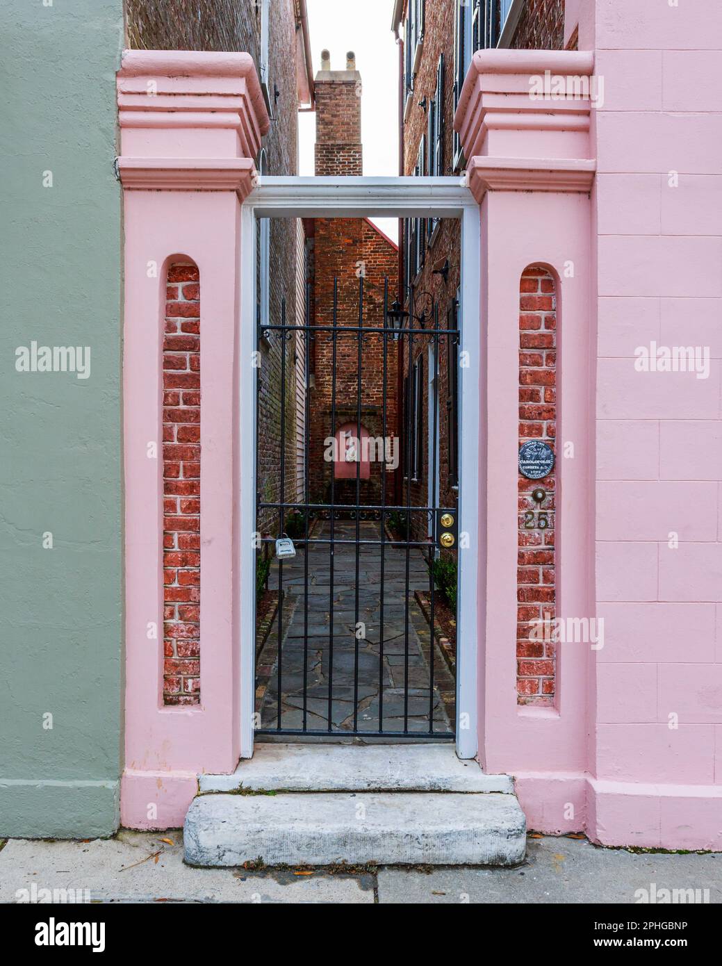 Gated alleyway in between a bright pink building and a light green ...