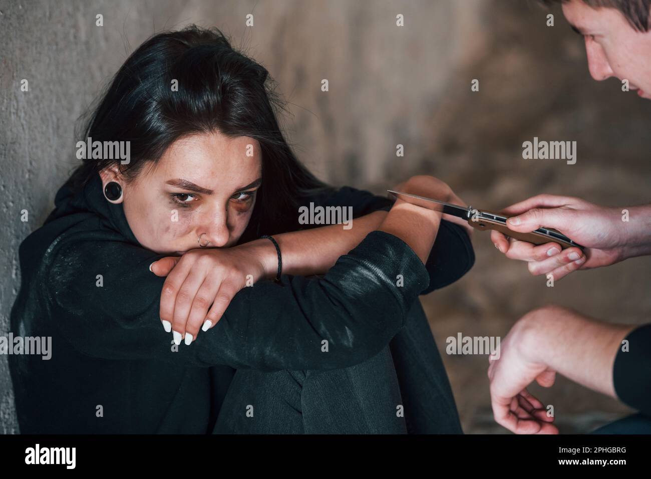 Kidnapped woman sitting and threatened by man with knife in hands in ...