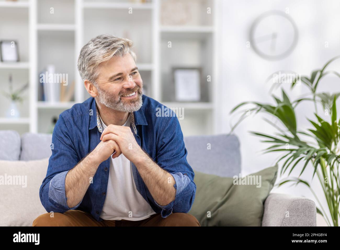 Portrait of a scary handsome gray-haired man in a blue shirt sitting at ...