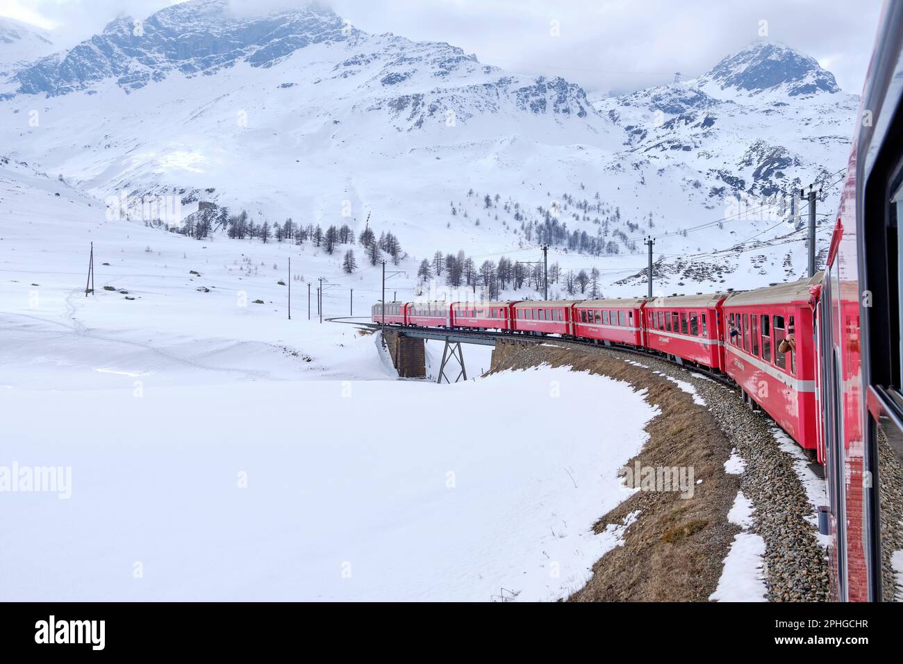 Bernina mountain pass. The famous red train is crossing the white lake ...