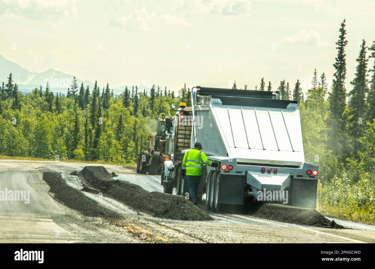 Roadwork on blacktop highway with workman in safety shirt by truck with ...