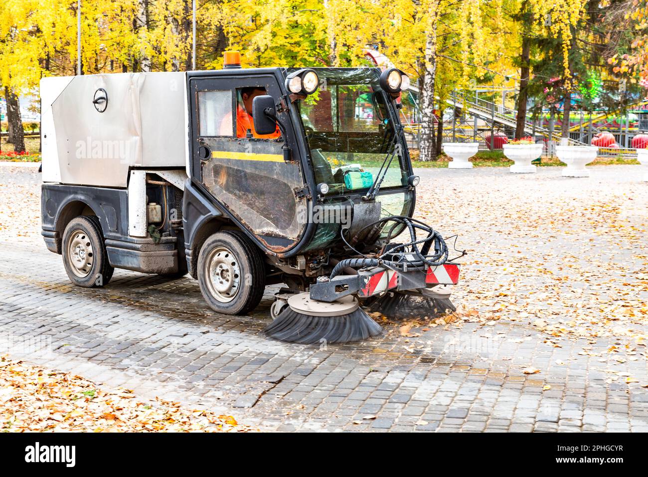 Street cleaning machine on a city street sweeps fallen leaves in autumn ...