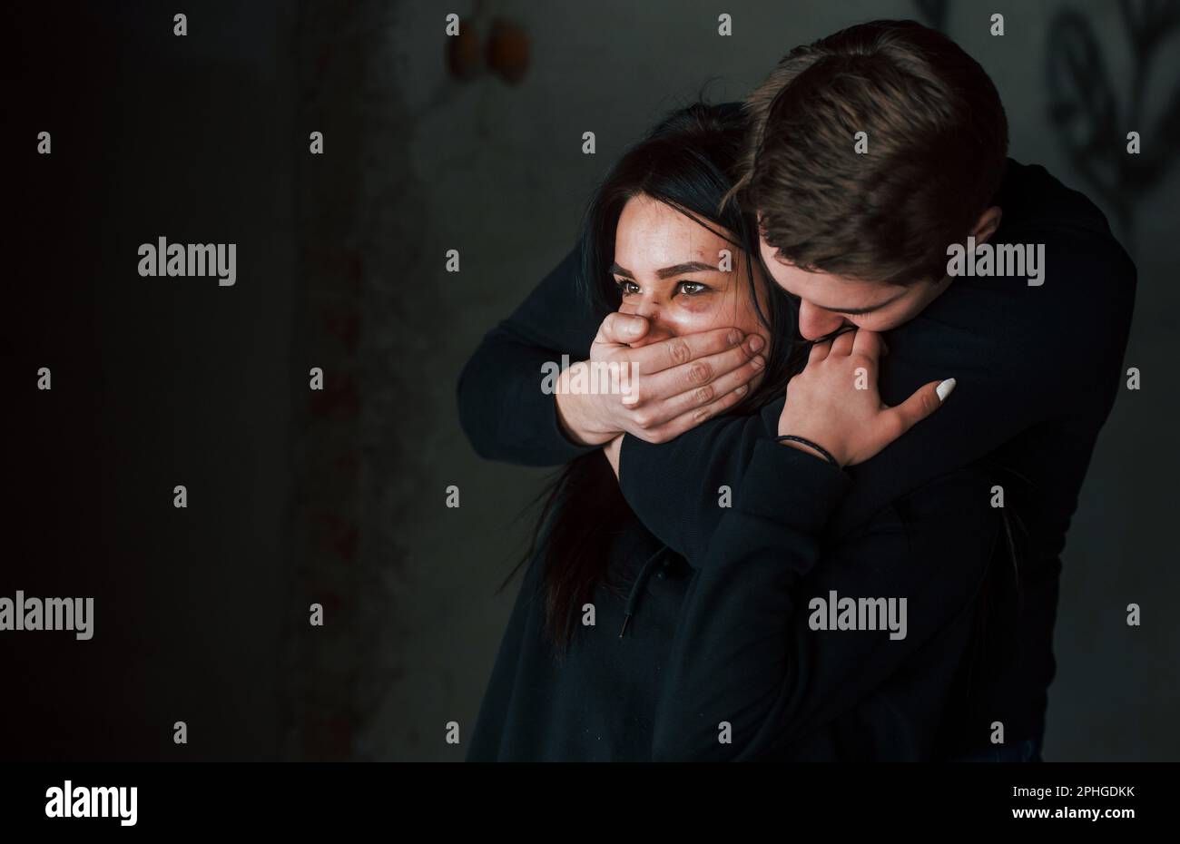 Man's hand covering her mouth. Kidnapped woman is threatened by guy ...