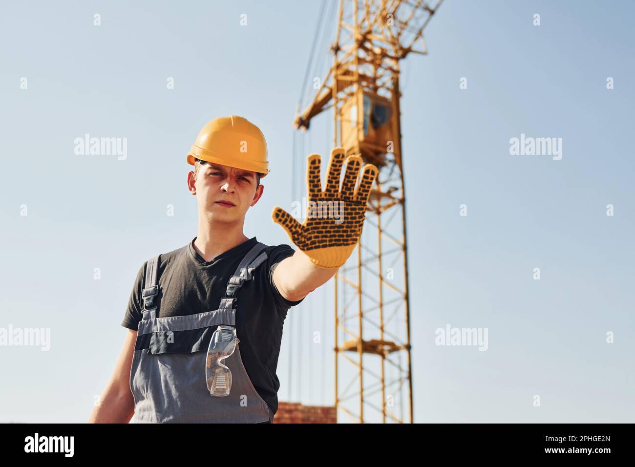 Shows stop sign by hand. Construction worker in uniform and safety ...