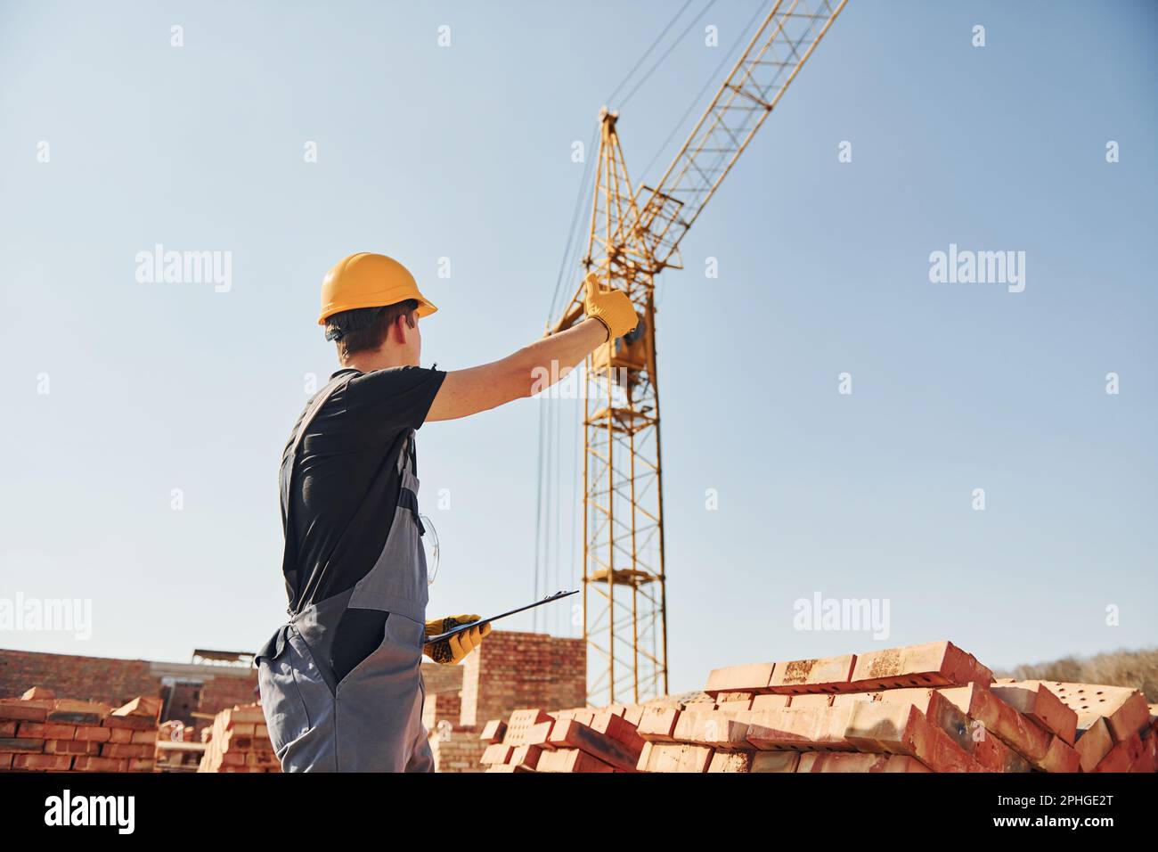 Communicating with crane guy. Construction worker in uniform and safety ...
