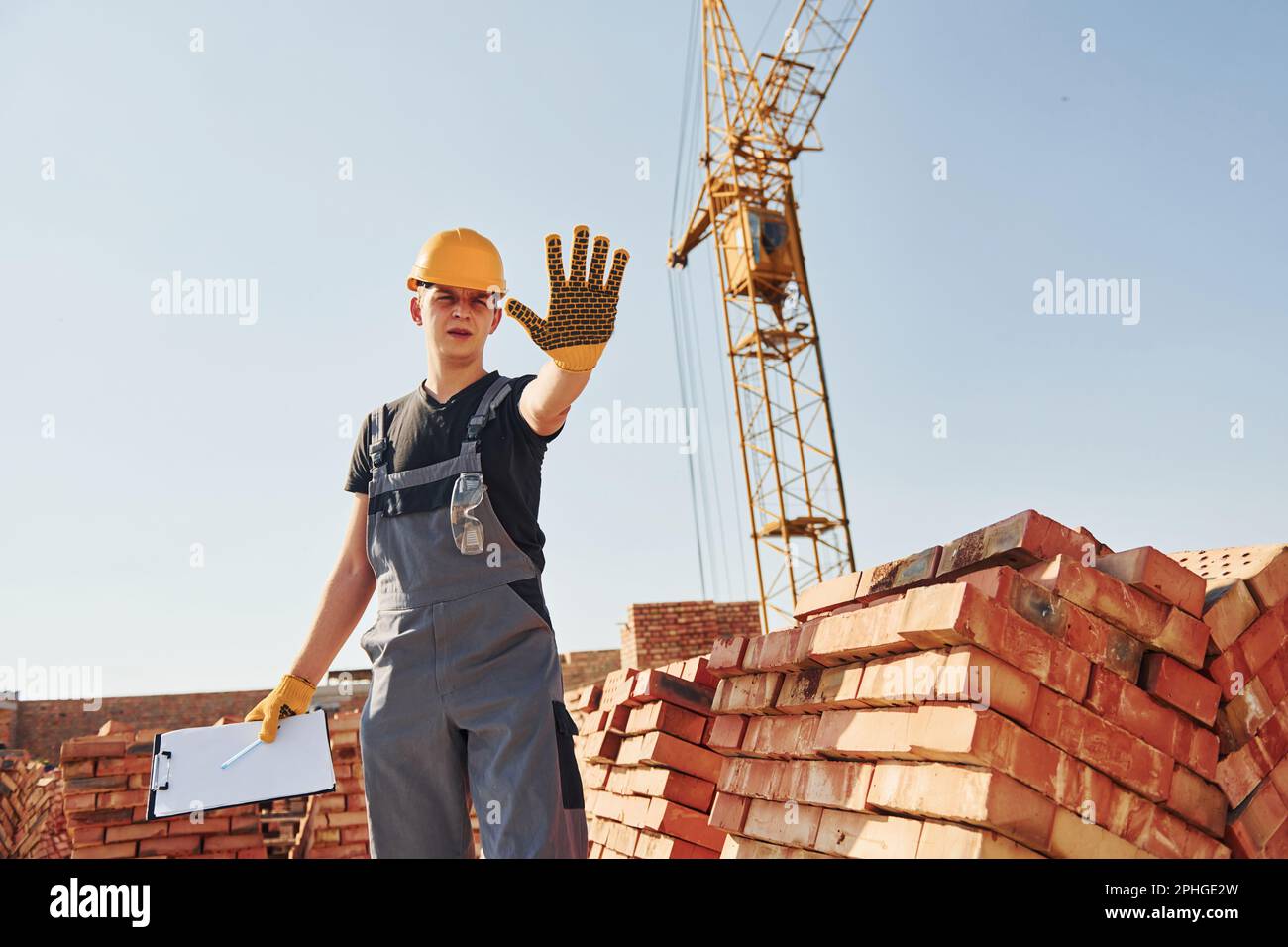 Shows stop sign by hand. Construction worker in uniform and safety ...