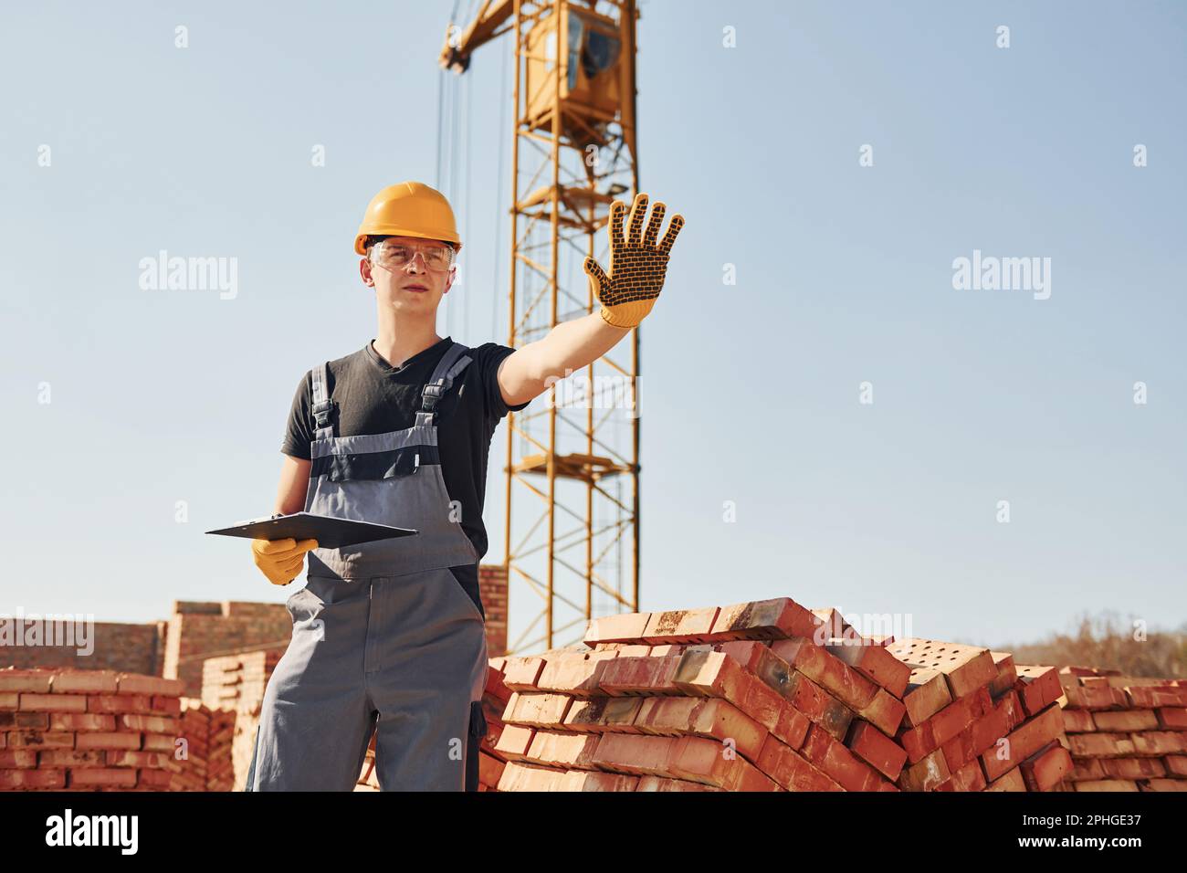 Shows stop sign by hand. Construction worker in uniform and safety ...