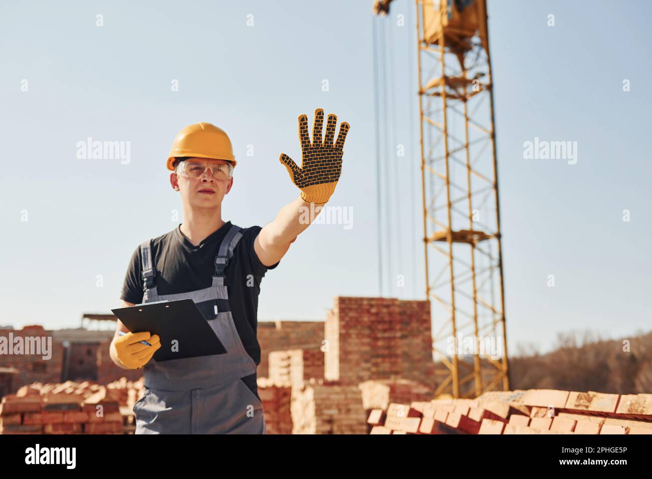 Shows stop sign by hand. Construction worker in uniform and safety ...