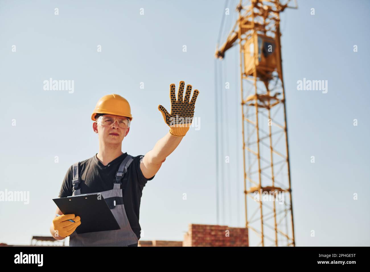 Shows stop sign by hand. Construction worker in uniform and safety ...