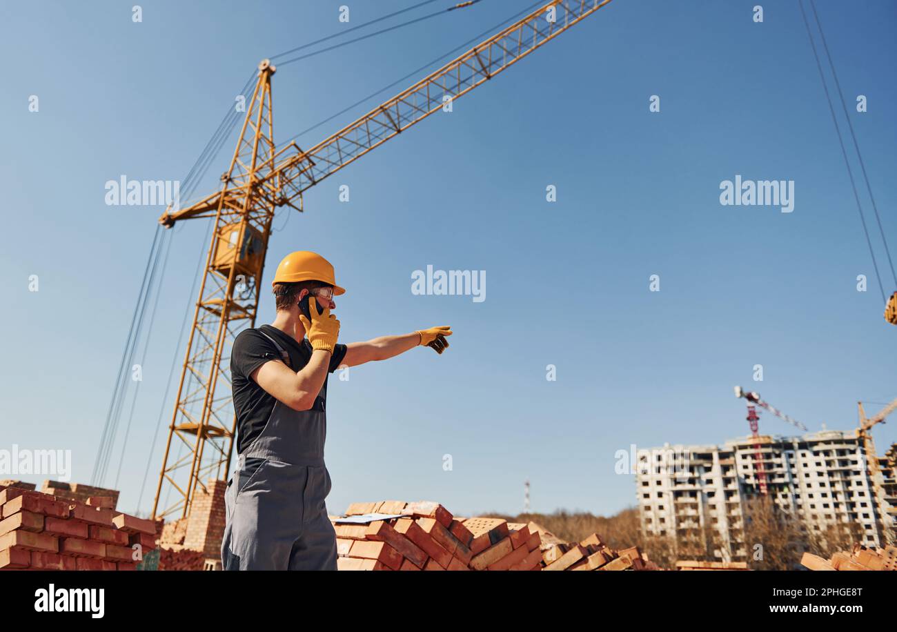 Talking by phone. Construction worker in uniform and safety equipment ...
