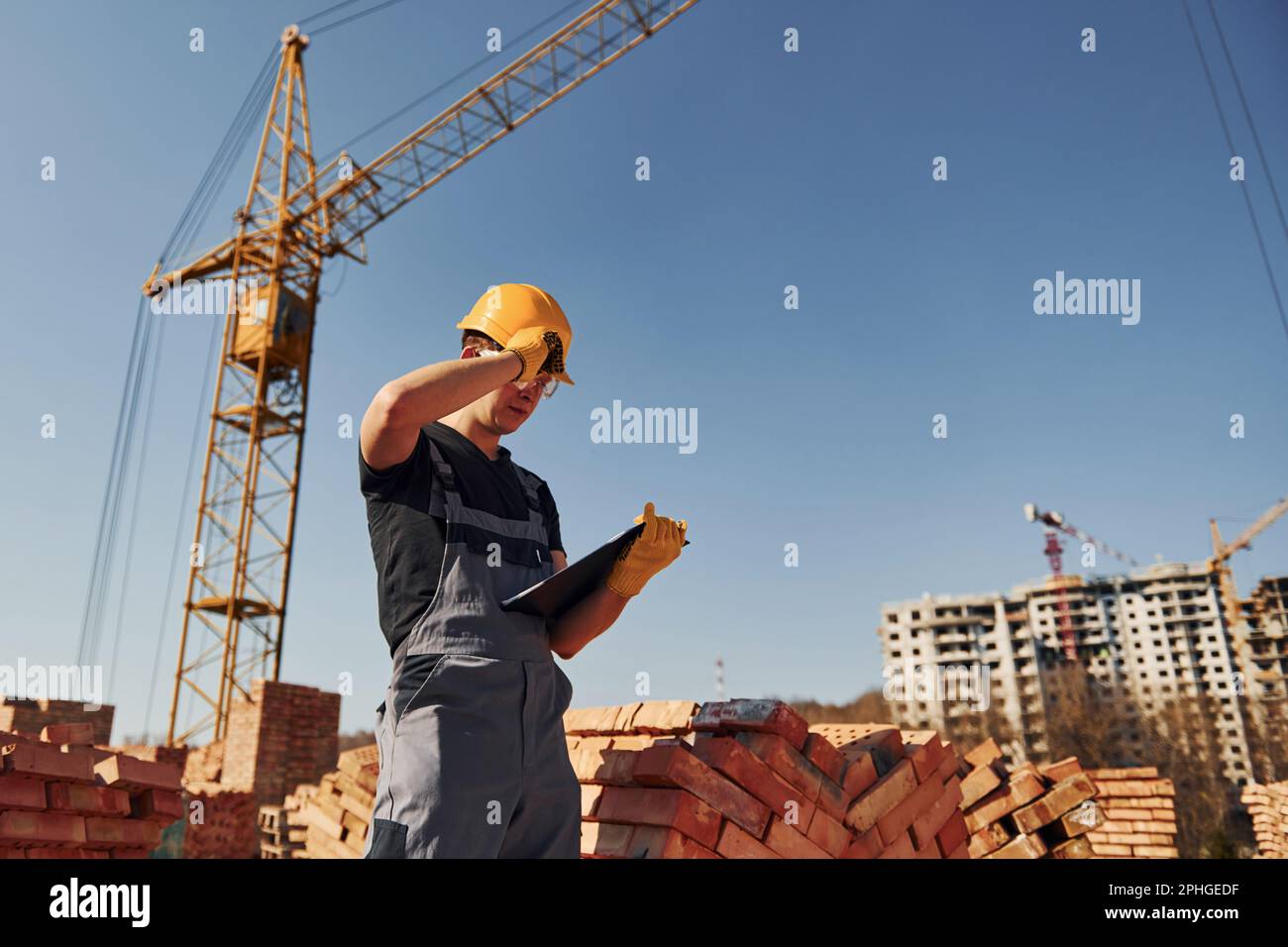 Holds notepad with documents. Construction worker in uniform and safety ...