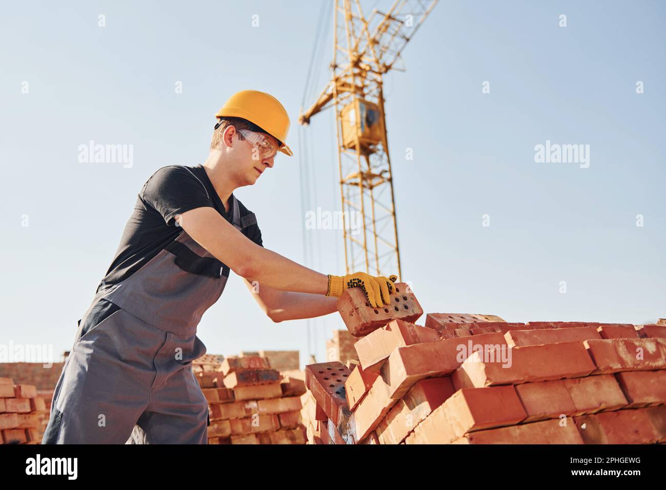 Installing brick wall. Construction worker in uniform and safety ...