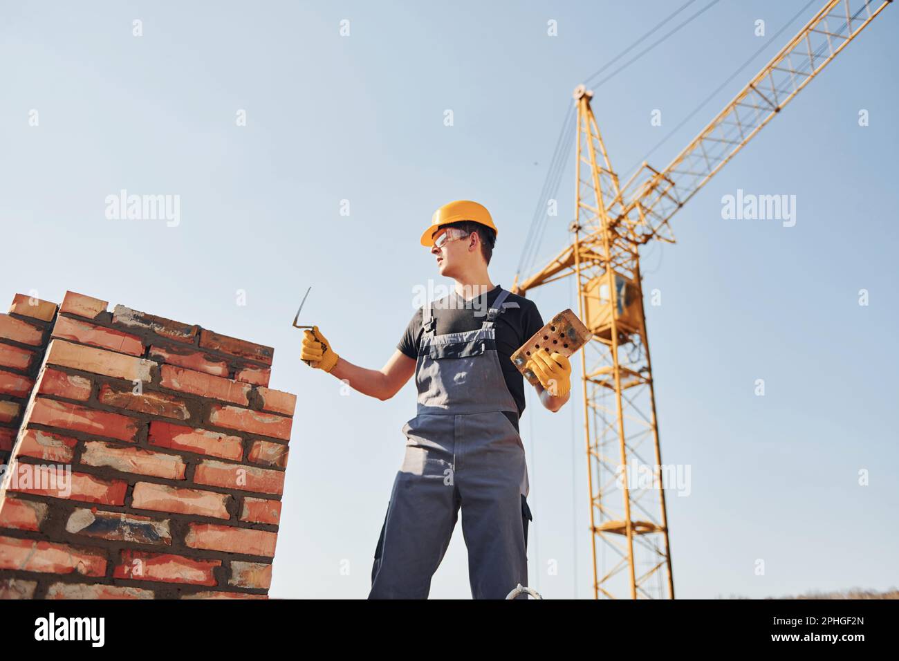 Installing brick wall. Construction worker in uniform and safety ...