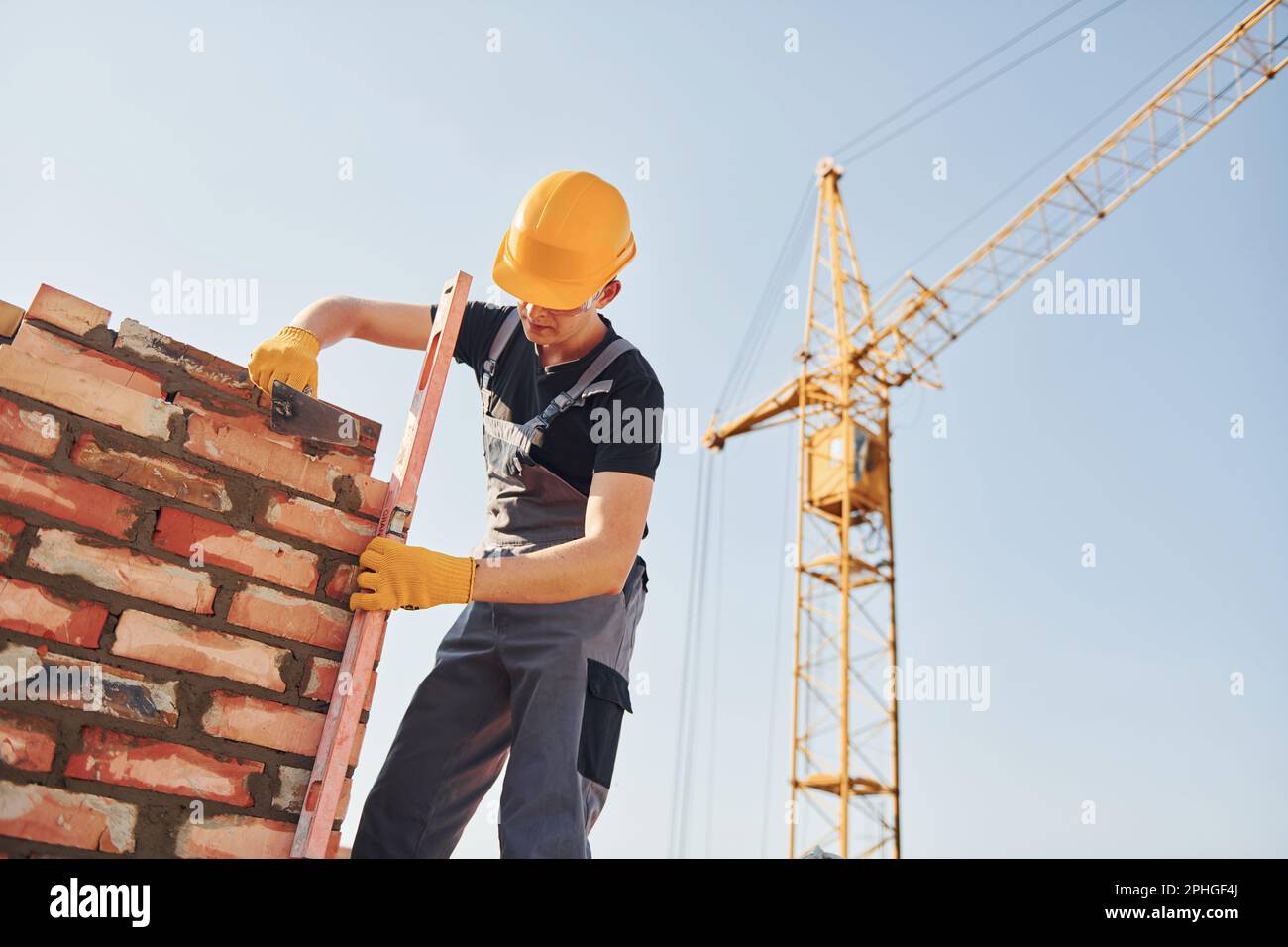 Installing brick wall. Construction worker in uniform and safety ...