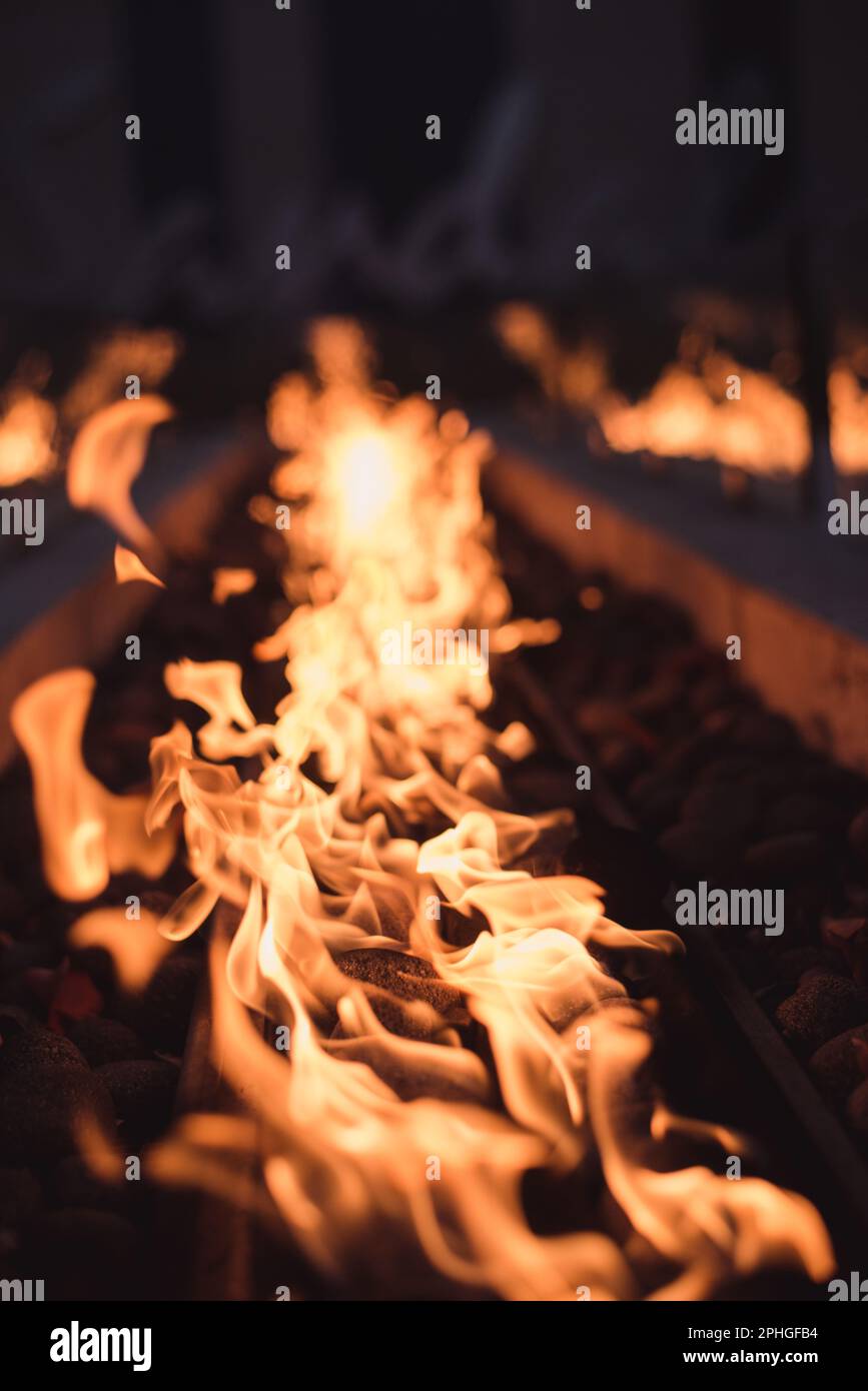 A closeup of a charcoal grill with burning embers, set against a ...