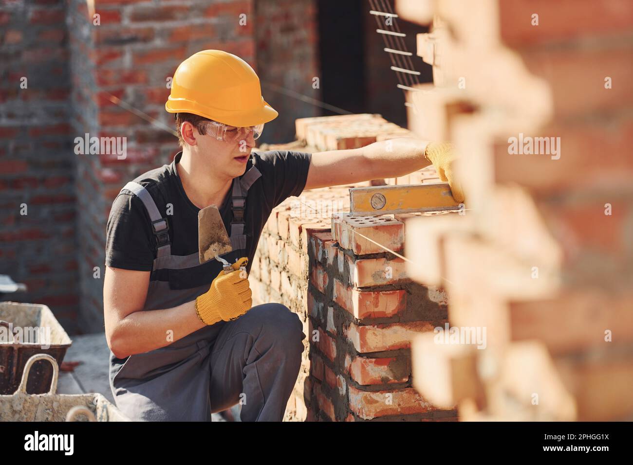Measures of brick wall. Construction worker in uniform and safety ...