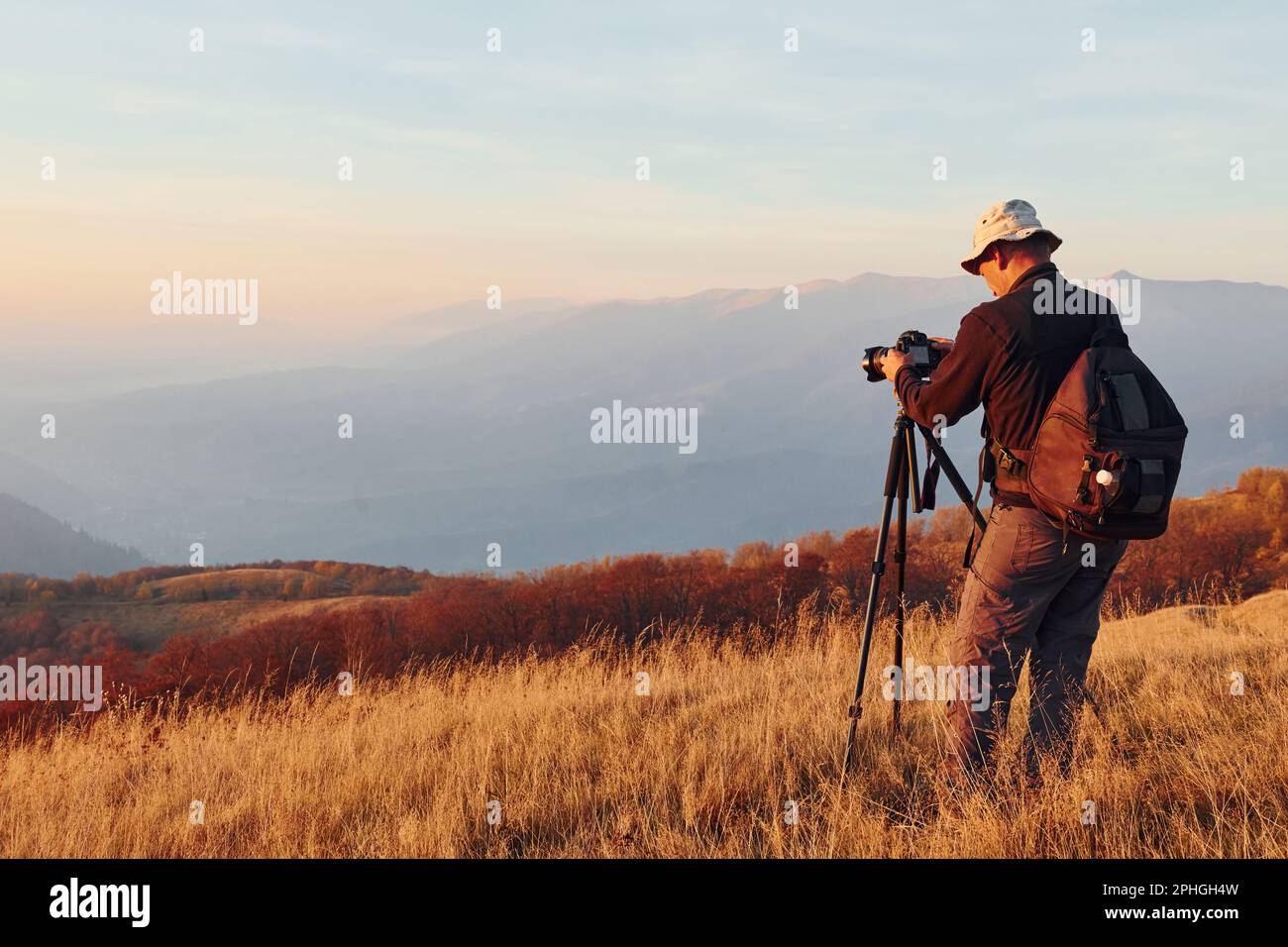 Male photographer standing and working at majestic landscape of autumn ...