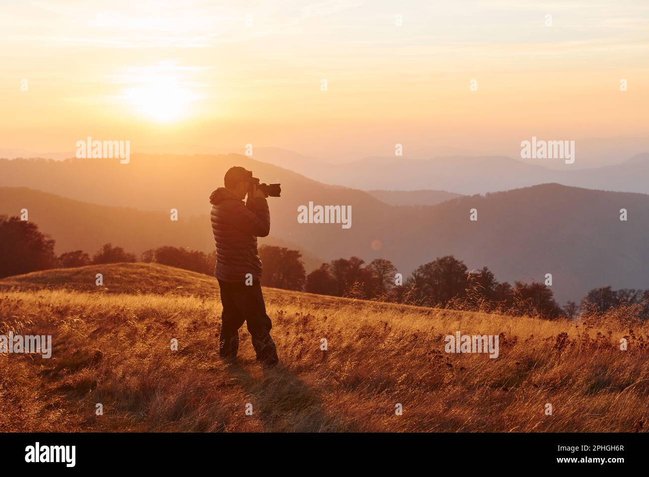 Male photographer standing and working at majestic landscape of autumn ...