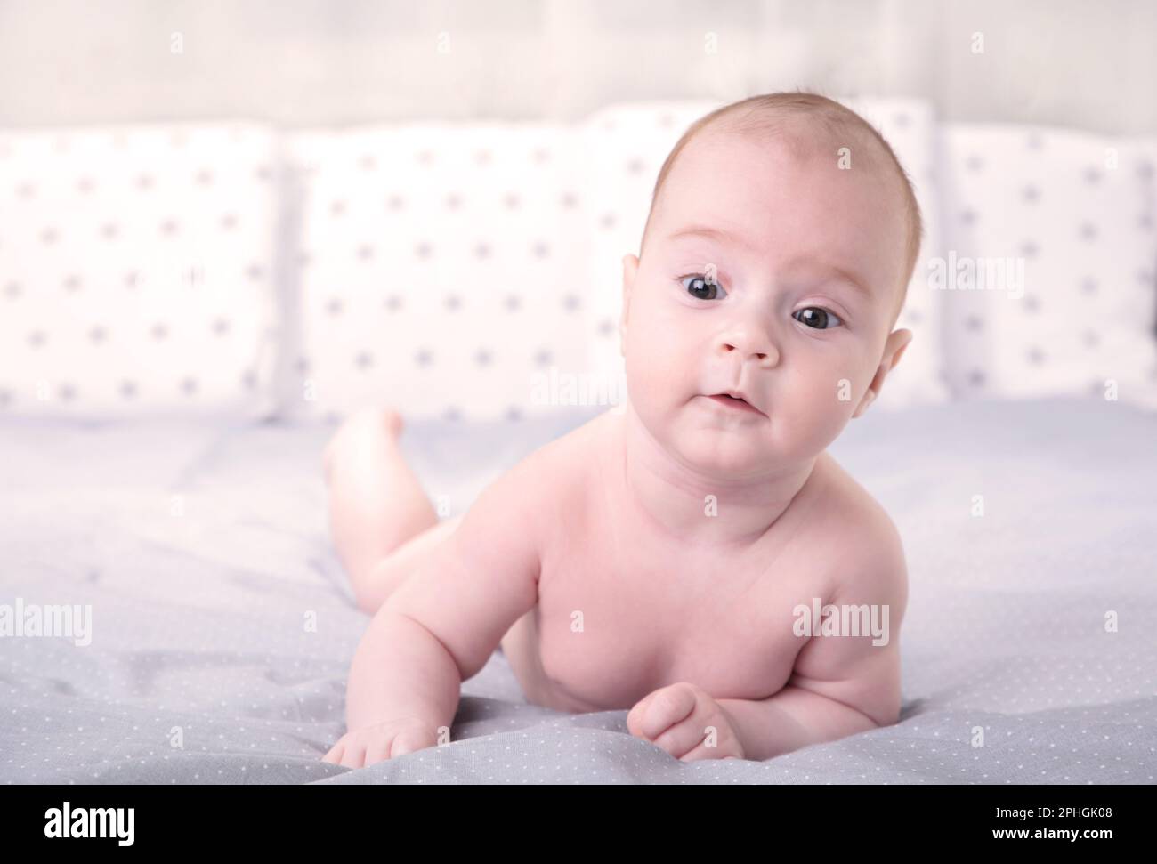 Happy young baby lying on tummy on a white bed. Top view Stock Photo - Alamy