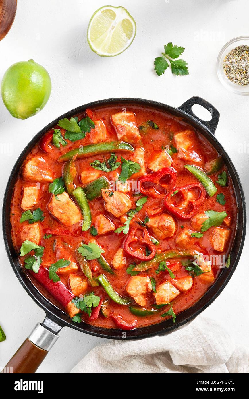 Thai style red chicken curry with vegetables in skillet over white ...