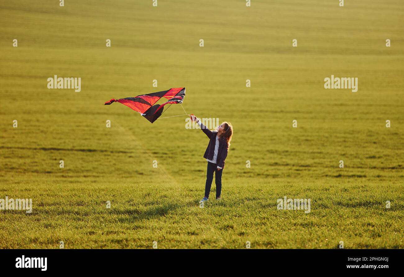 Happy little girl running with kite in hands on the beautiful field ...