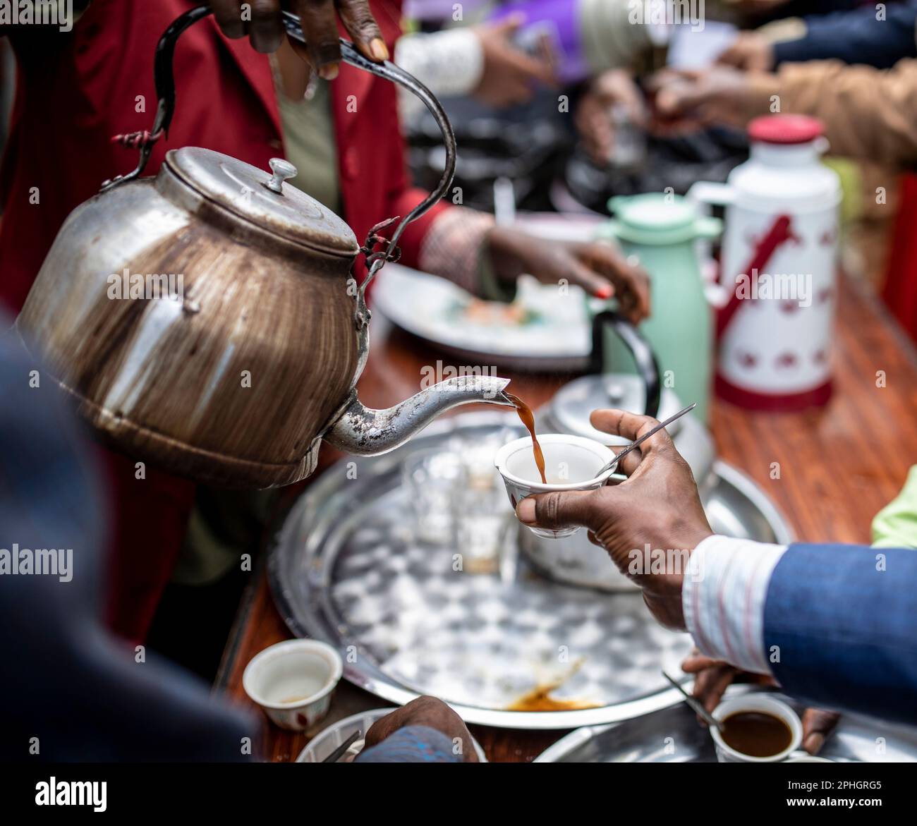 Pouring dark coffee from a communal pot into cups in Ethiopia Stock ...